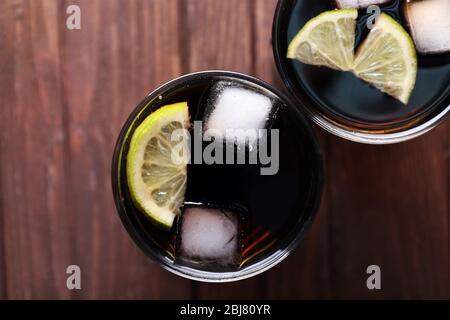 Cocktails with lime slices and ice blocks on wooden table, close up ...