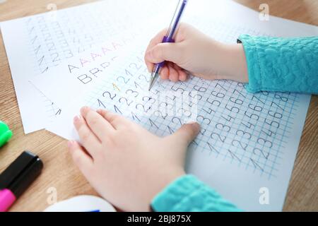 Little girl learning to write digits at the table Stock Photo - Alamy