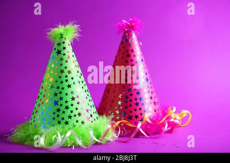 Funny party hats on purple background Stock Photo - Alamy