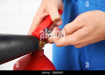 male hands pulling safety pin of fire extinguisher Stock Photo - Alamy