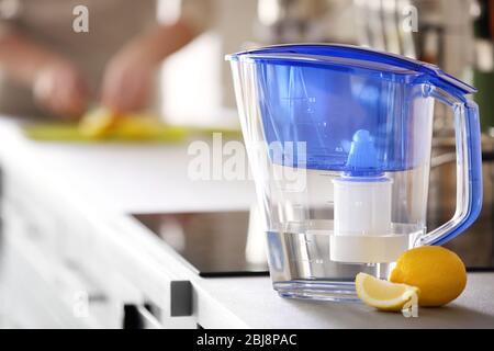 Water filter jug and lemon on light grey table in kitchen Stock Photo ...