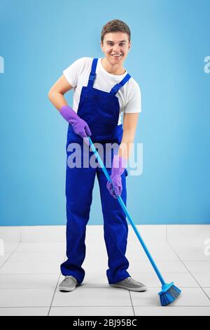 Man holding broom on grey background Stock Photo - Alamy