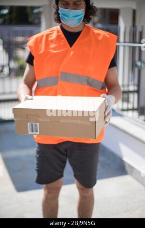 portrait of young caucasian delivery man holding and carrying cardbox ...