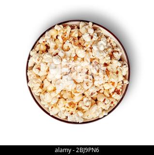 A top view closeup of a popcorn bowl with some corns spilled around it ...