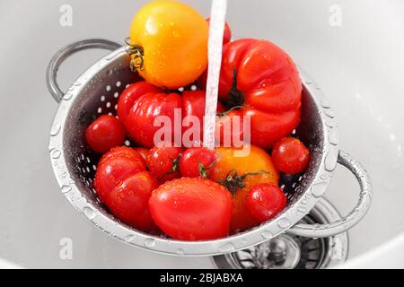 Water flowing into colander with tomatoes in kitchen sink Stock Photo ...