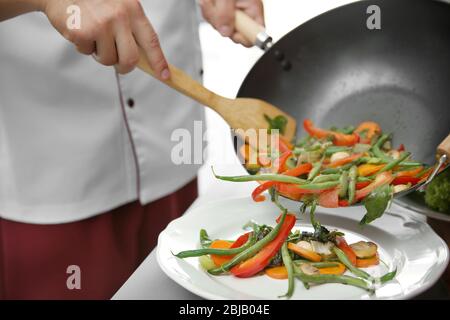 Female hand putting cooked vegetables on plate closeup Stock Photo - Alamy