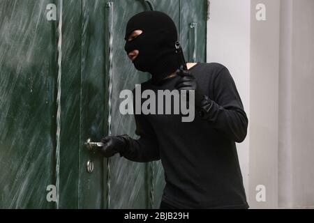 Armed thief breaking a door Stock Photo - Alamy