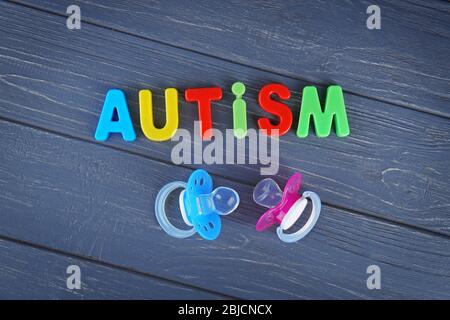 Word Autism with pacifiers on wooden background Stock Photo - Alamy