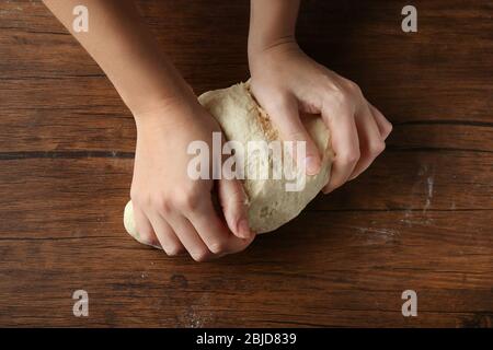 close view of a young woman kneading dough in a home kitchen on top of ...