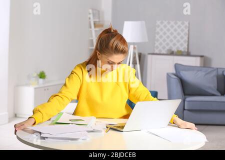 Confused young woman calculating taxes at home Stock Photo - Alamy