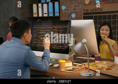 Young programmers eating pizza while working in office Stock Photo - Alamy