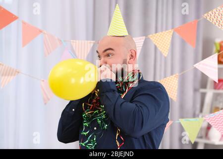Funny fat man inflating balloon at birthday party Stock Photo - Alamy