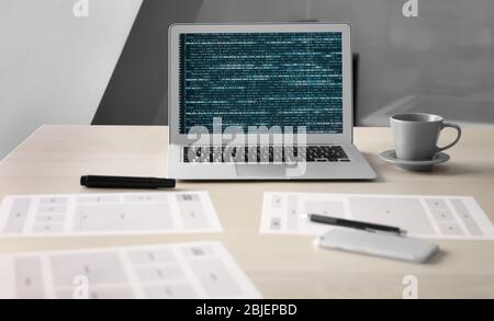 Laptop with programming code and coffee cup in office desk. Low depth ...
