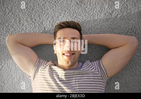 Young man lying on soft mattress against color background Stock Photo ...
