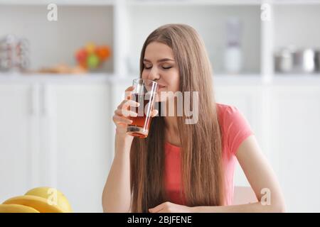 Young woman tasting fresh juice sitting on couch at living room Stock ...