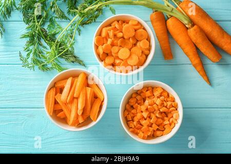 Different cuts of carrot in bowls on wooden background Stock Photo - Alamy