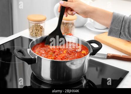 Woman cooking turkey chili on modern stove in kitchen Stock Photo - Alamy