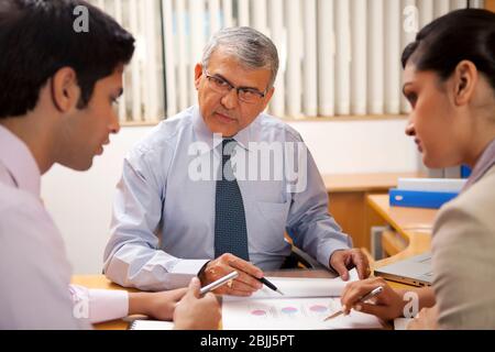 Manager wearing formals explaining to his employees Stock Photo - Alamy