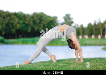 Young woman in grey costume practicing yoga near lake Stock Photo - Alamy