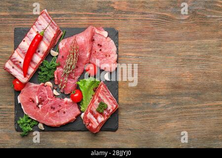 Slate plate with different types of meat on wooden table Stock Photo ...