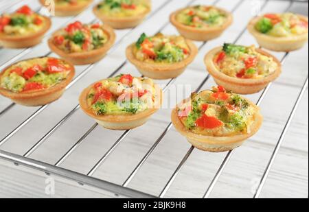 Baking grid with broccoli quiche tartlets on table Stock Photo - Alamy