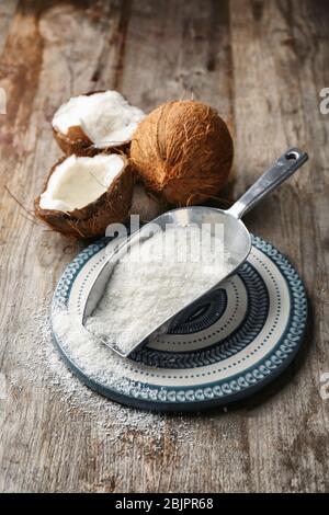 Scoop with desiccated coconut and flour in bowl on white background ...