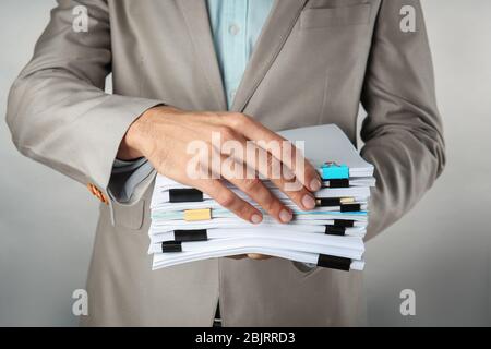 Man with stack of documents against light background Stock Photo - Alamy