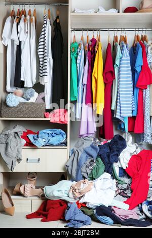 Messy wardrobe with different clothes indoors. Fast fashion concept ...