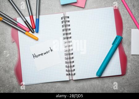 Notebook, sheet of paper with word "Homework" and stationery on grey ...