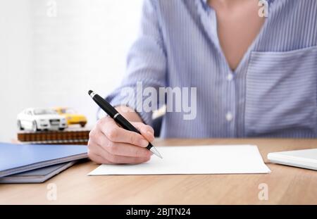 Woman filling in car insurance form at table Stock Photo - Alamy