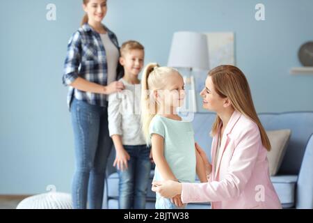 Mother leaving her children with nanny at home Stock Photo - Alamy
