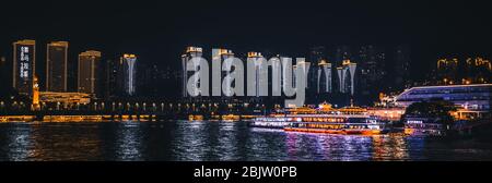Night view of a boat on the Yangtze River with high rise city buildings ...