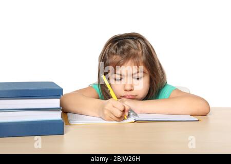 Cute little girl with lot of homework to do against white background ...