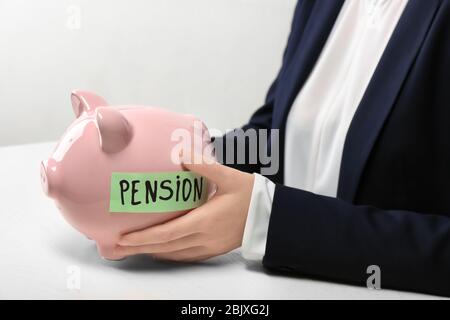 Woman and piggy bank with label "PENSION" at table Stock Photo - Alamy