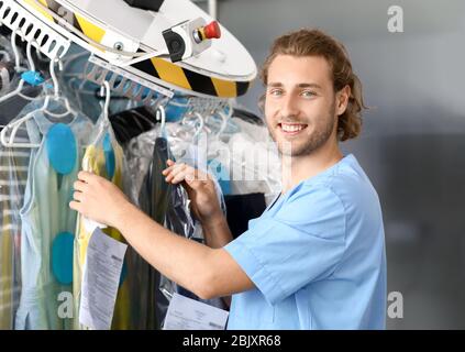 Worker of modern dry-cleaner's near rack with clothes Stock Photo - Alamy