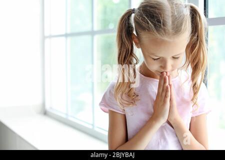 Praying little girl near window Stock Photo - Alamy