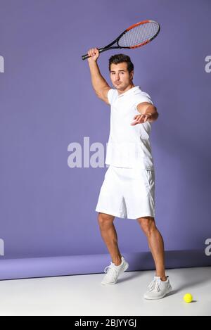 Handsome man playing tennis on color background Stock Photo - Alamy