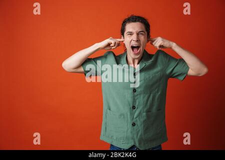 Image of caucasian displeased guy plugging his ears isolated over grey ...