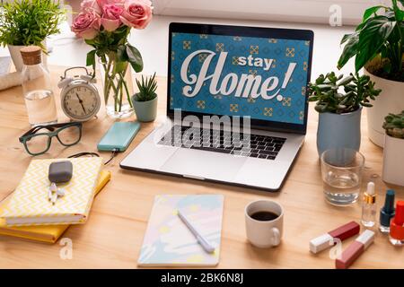 Alarm clock, modern laptop and eyeglasses on table in room, closeup ...