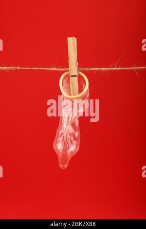 Close up one condom hanging on twine washing line with wooden ...