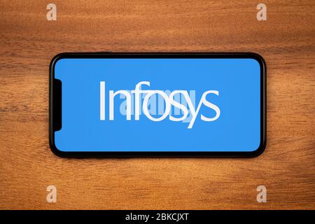 A smartphone showing the Infosys logo rests on a yellow background ...