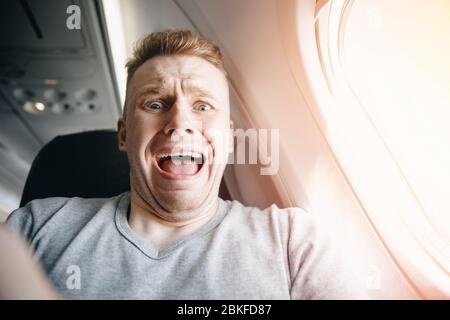 Male passenger in plane screams and cries, aerophobia. background of ...
