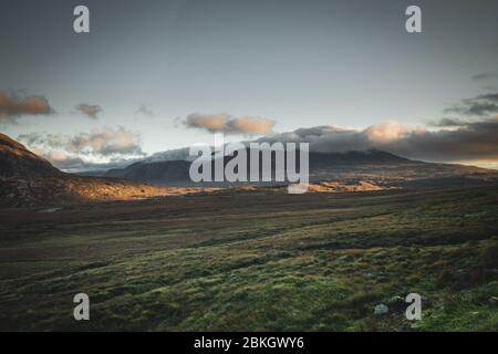 Foinaven mountain range capped in sunset clouds at autumn in the North ...