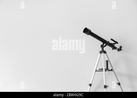 Modern telescope near light wall Stock Photo - Alamy