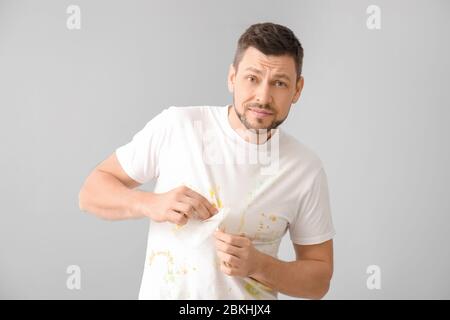 Displeased man in dirty clothes on light background Stock Photo - Alamy