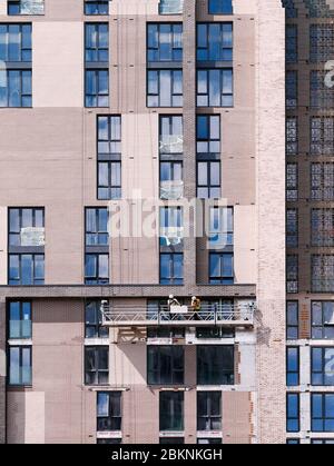 Suspended construction cradle on the background facade of the building ...