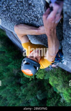 A man climbing a technical granite crack system high over a valley ...