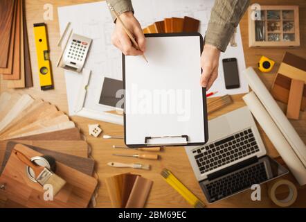 Hands holding construction tools and clipboard on yellow background ...