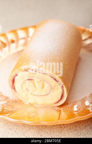 Arctic roll cake on a plate on a tray next to a spoon and a fork on a ...