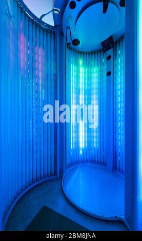 vertical Solarium with glowing blue light ultraviolet lamps for tanning ...